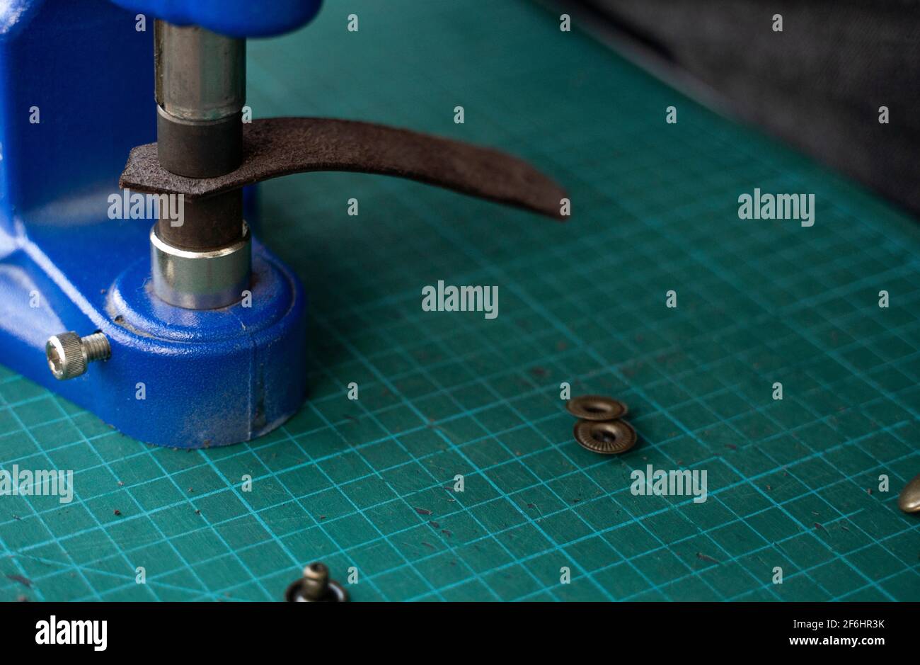 Artisan using hand press for setting snaps in leather for makes a ...