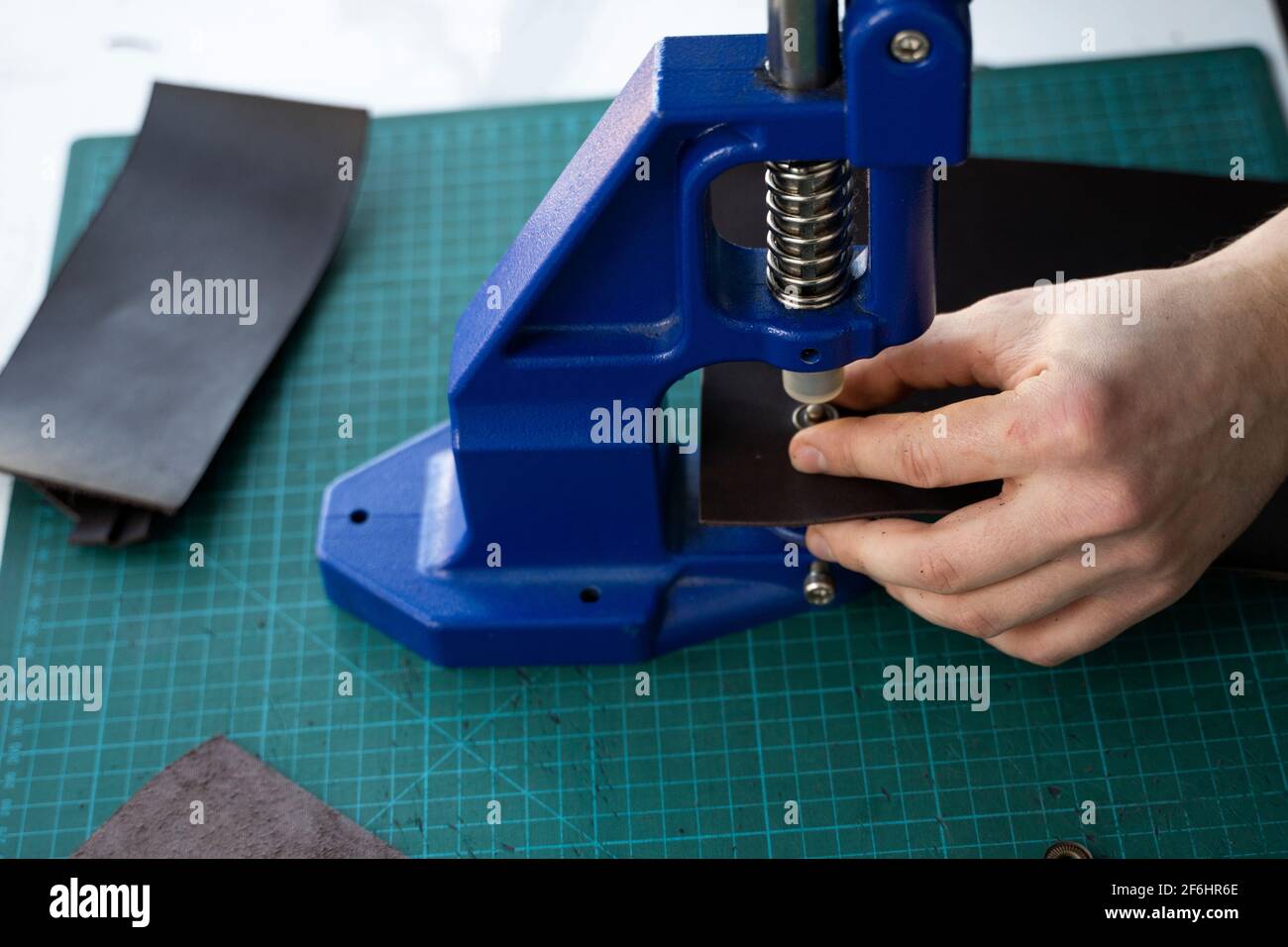 Artisan using hand press for setting snaps in leather for makes a ...