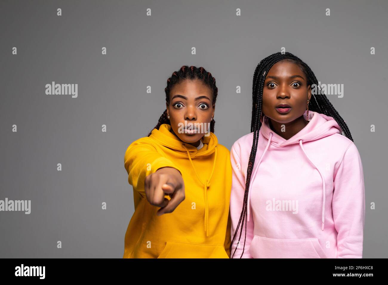 Two young african women are scared about something pointing fingers at ...