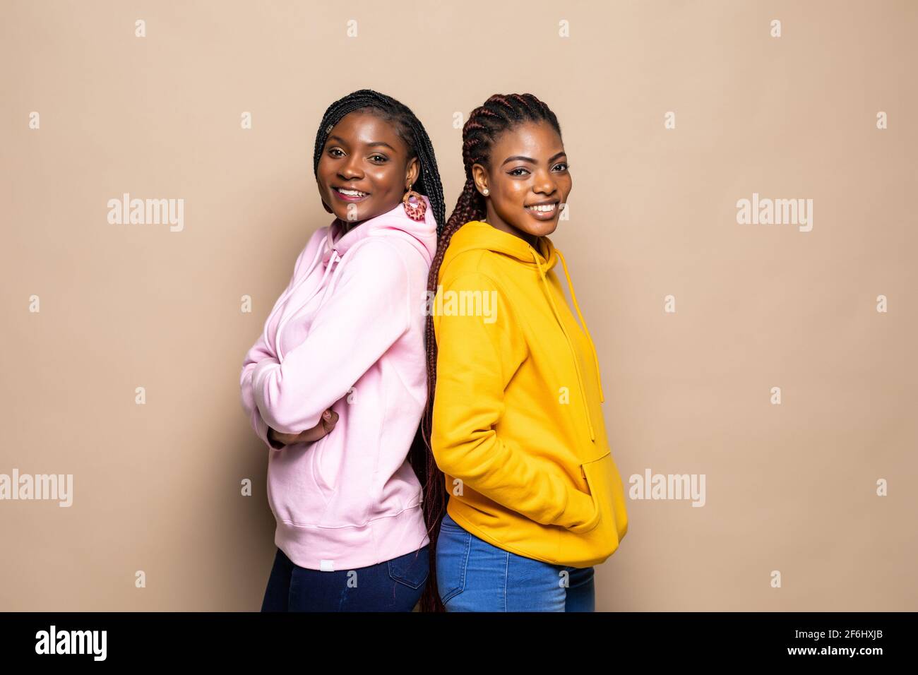 Portrait of two cheerful young women standing together and looking at ...
