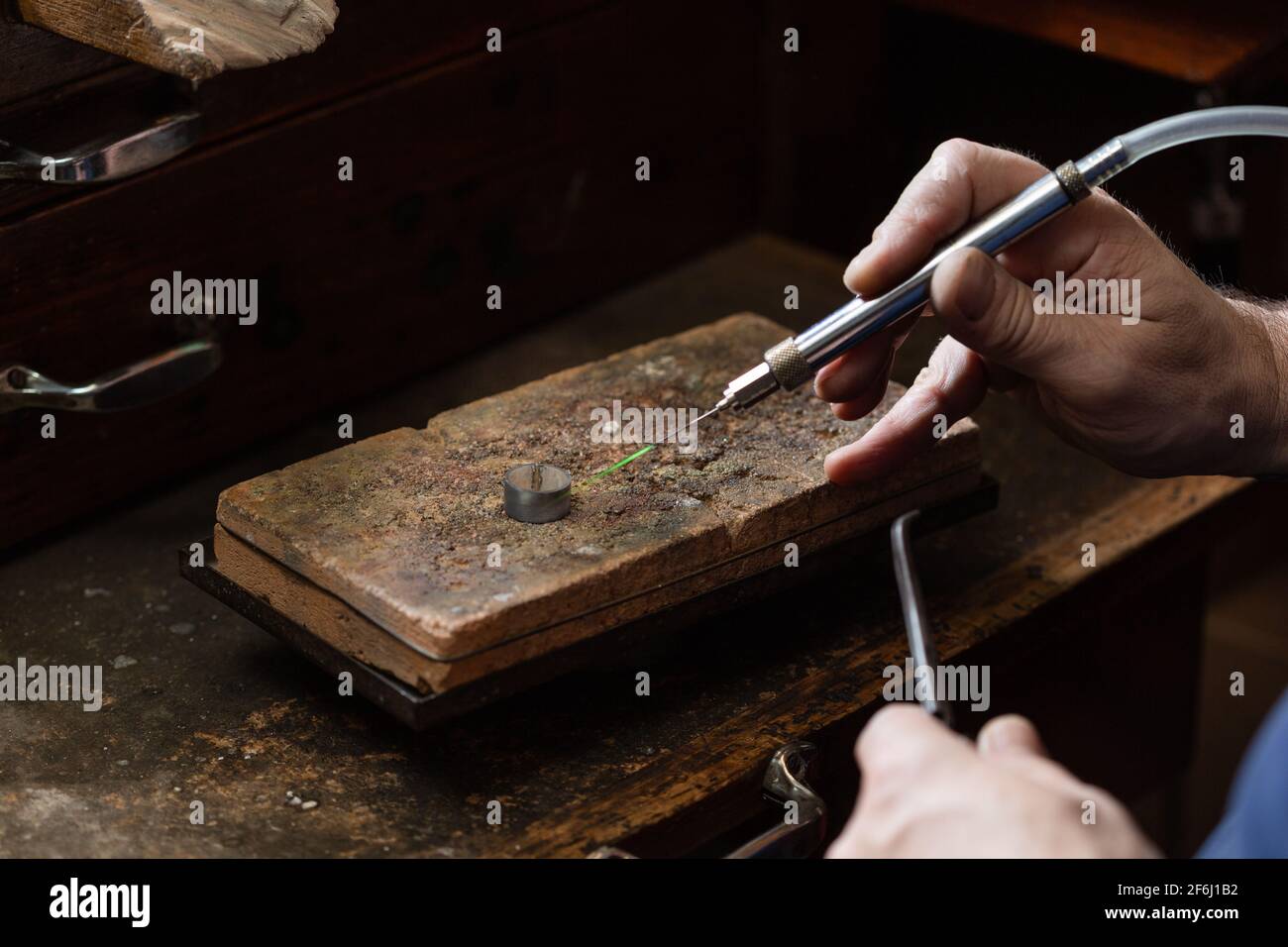 goldsmith jeweler soldering a silver ring on the workbench with a ...