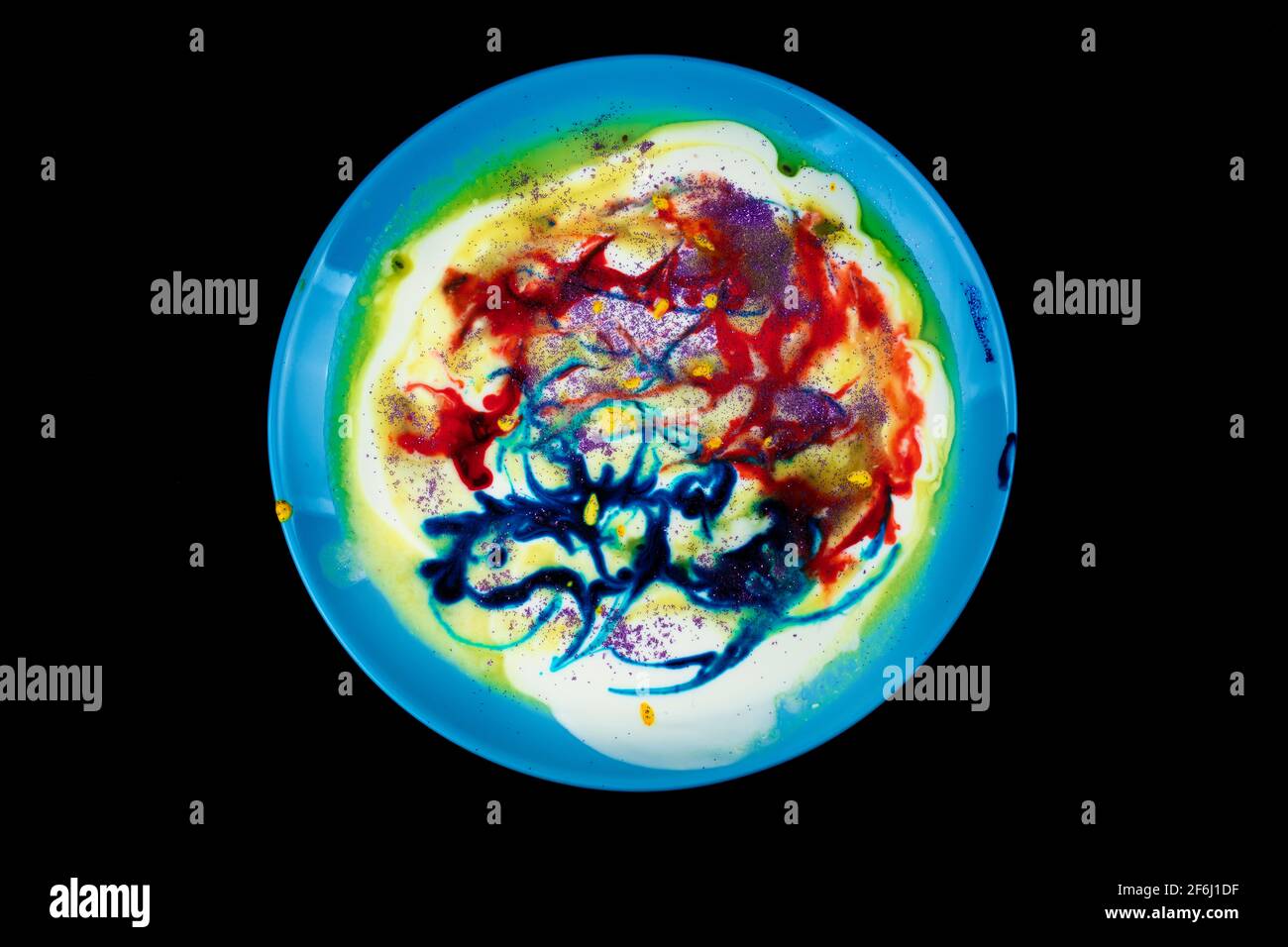 On a white plate, smeared ink multicolored paints on a black background ...