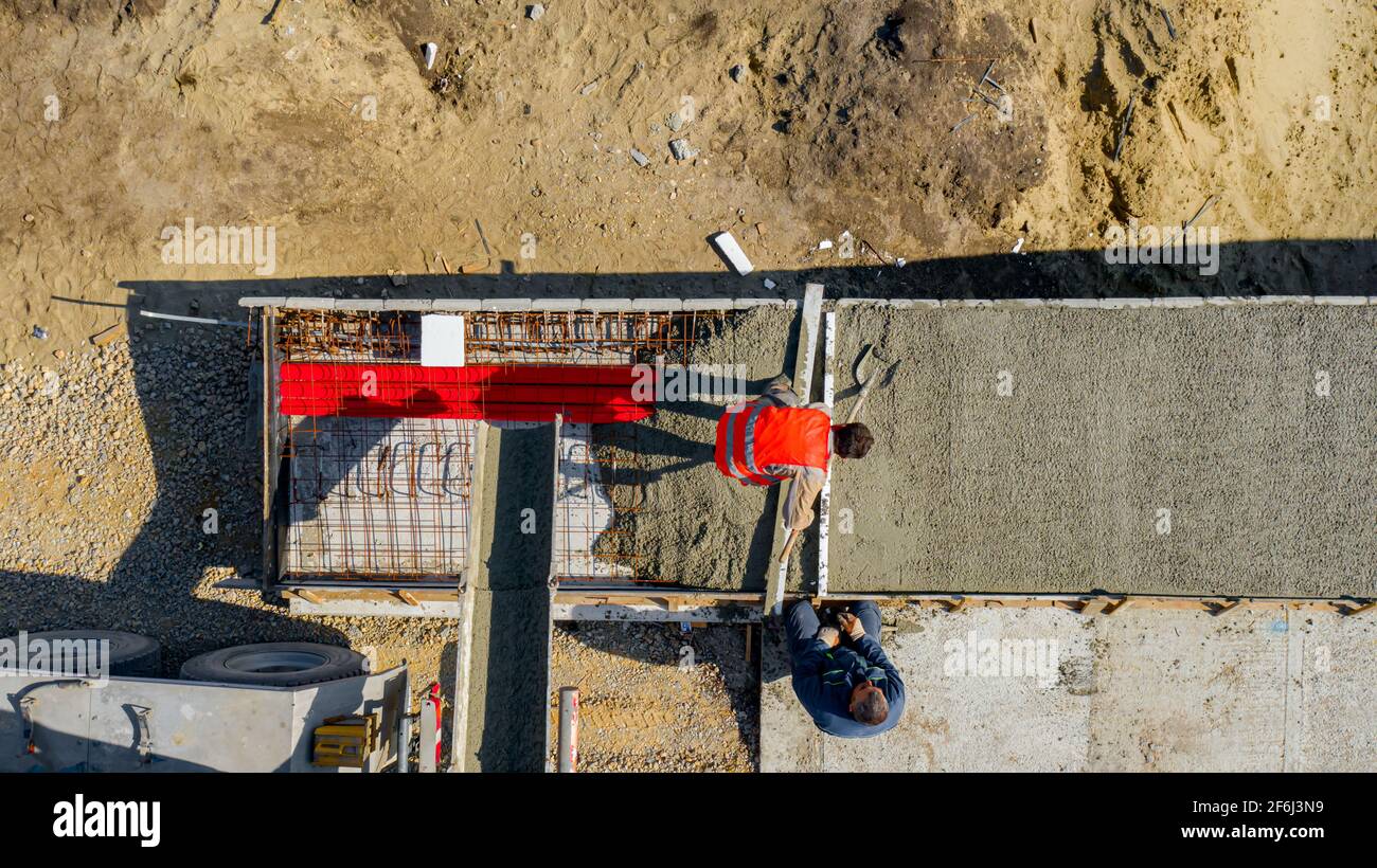 Above top view, overhead on construction workers are leveling fresh ...