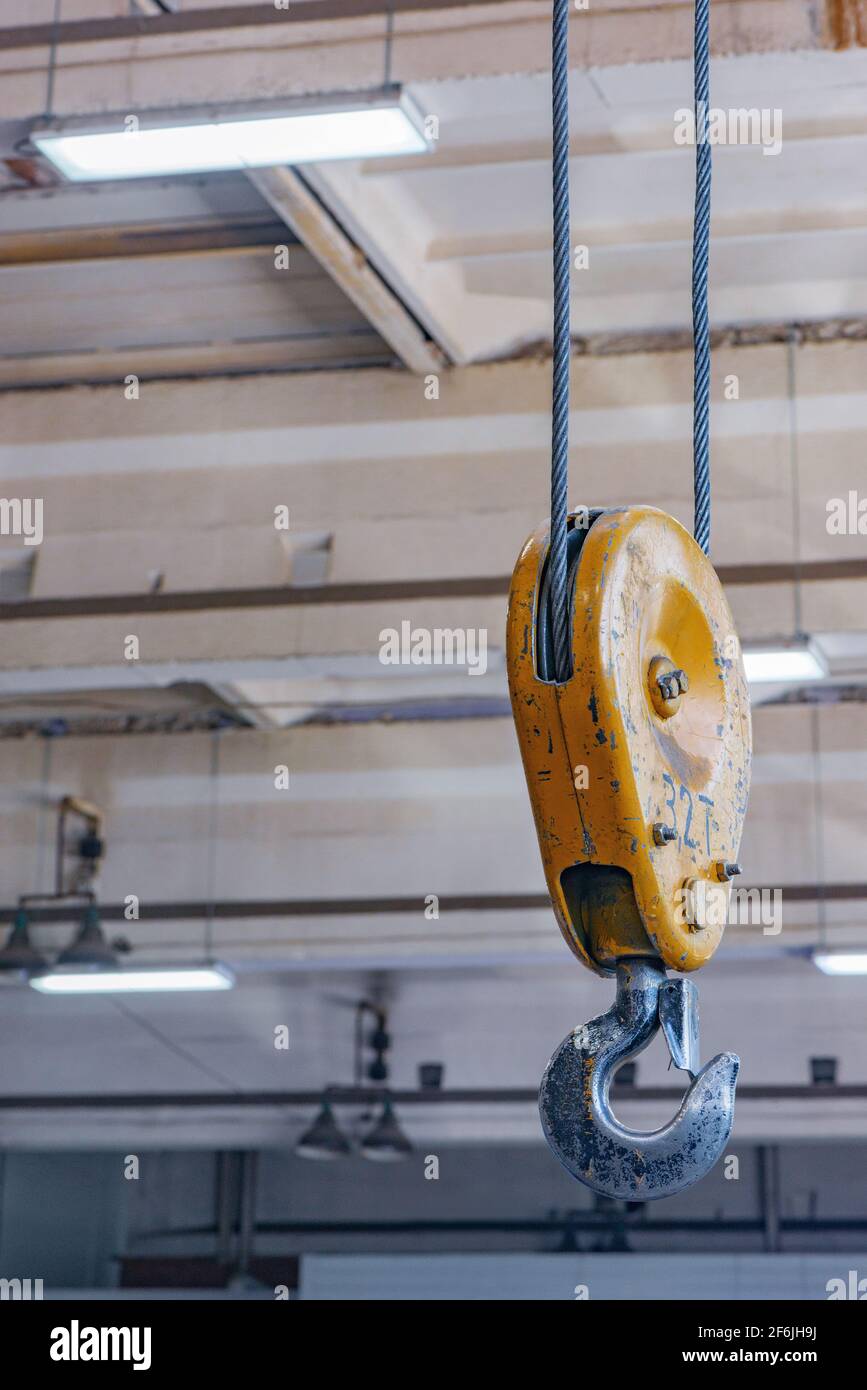 Crane hooks with chains hanging on steel ropes inside of the plant ...