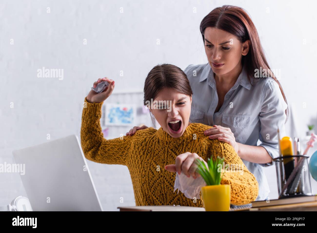 angry teenage girl tearing paper and screaming near worried mother ...