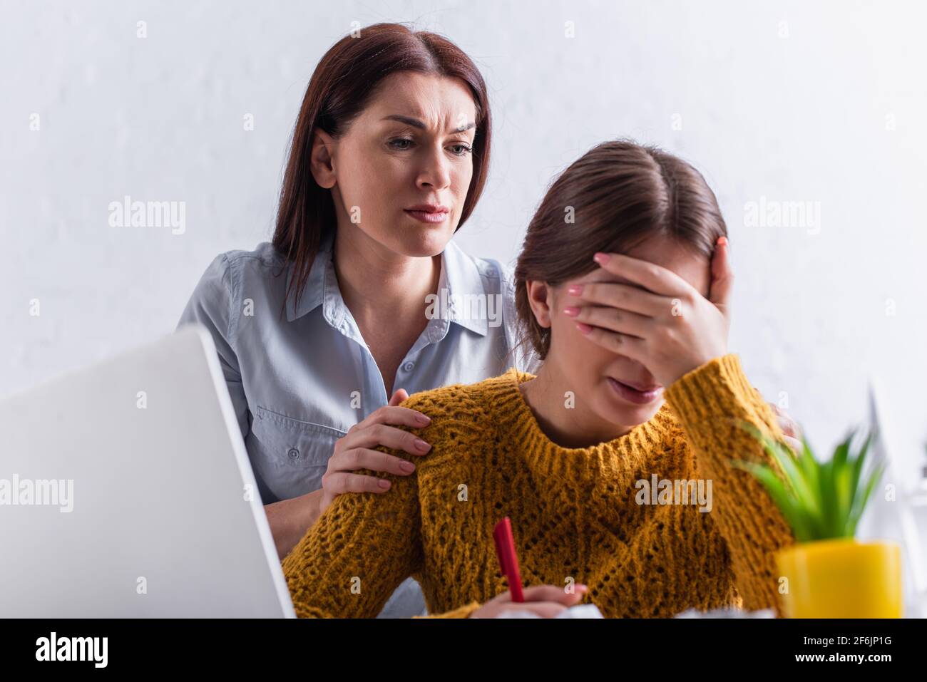 worried mother hugging upset teenage daughter crying while studying online at home Stock Photo ...
