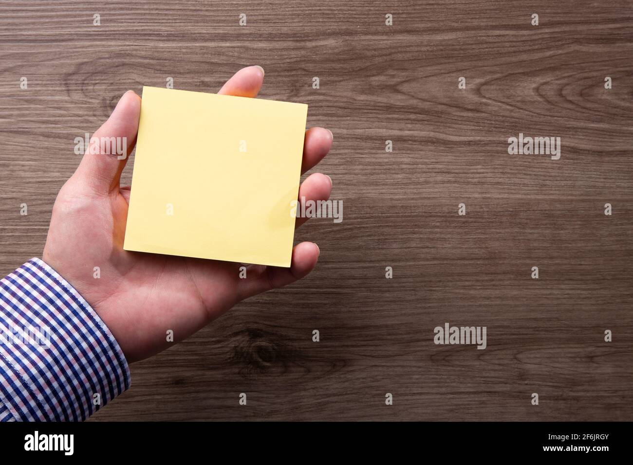 Hand holding sticky post note paper sheet on wooden background Stock ...