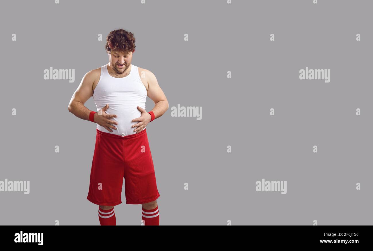 Slightly overweight man looking at his belly fat standing isolated on ...
