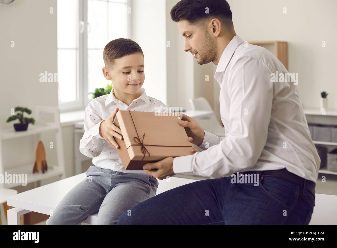 Happy little son giving a box with a birthday or Father's Day present ...