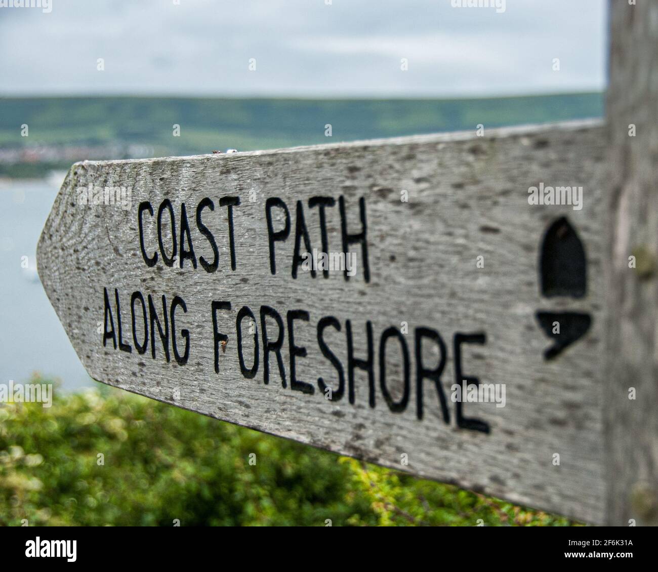 A weathered wooden sign post indicating the route of a coastal path ...
