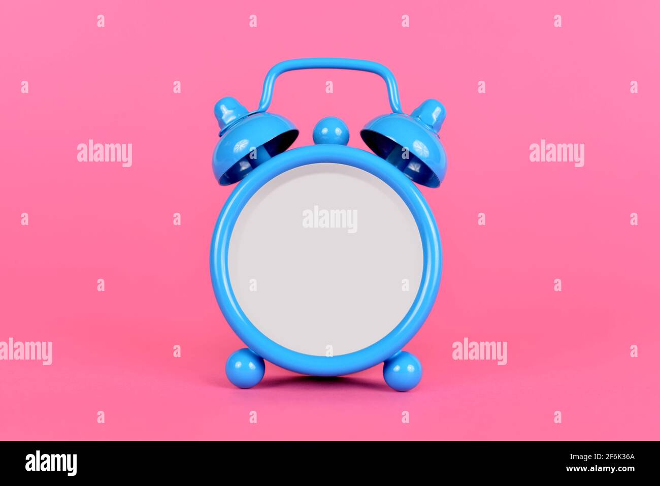 Blue classic alarm clock without hands and numbers on pink background ...