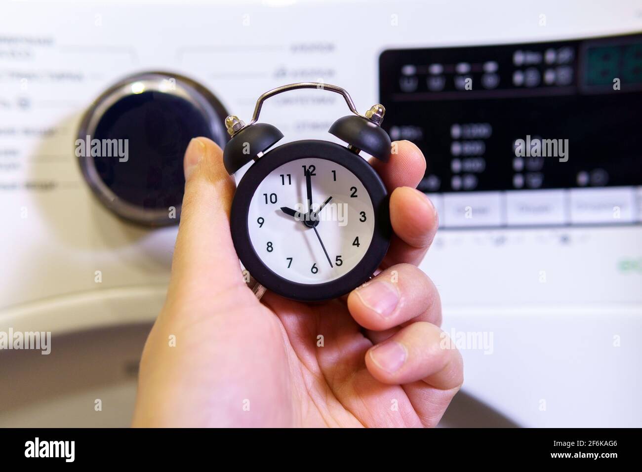 Washing clothes. Time to wash your dirty laundry. alarm clock in hand ...