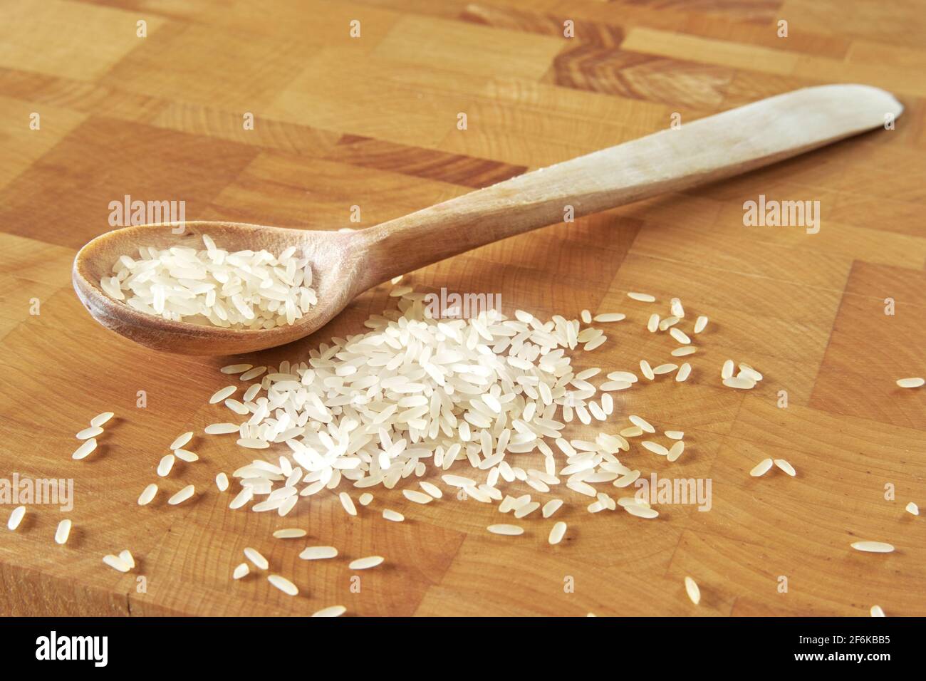 Wooden spoon and rice on chopping board Stock Photo - Alamy