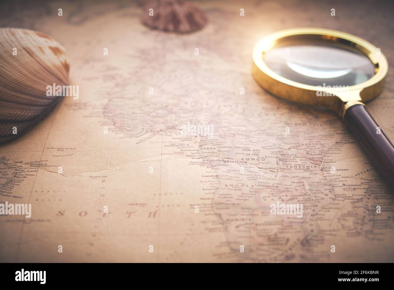 Old retro map of world is pressed with shells and magnifying glass ...