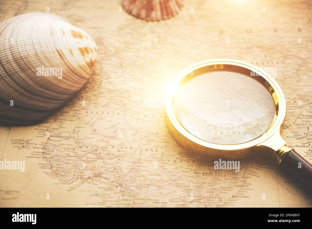 Old retro map of world is pressed with shells and magnifying glass ...