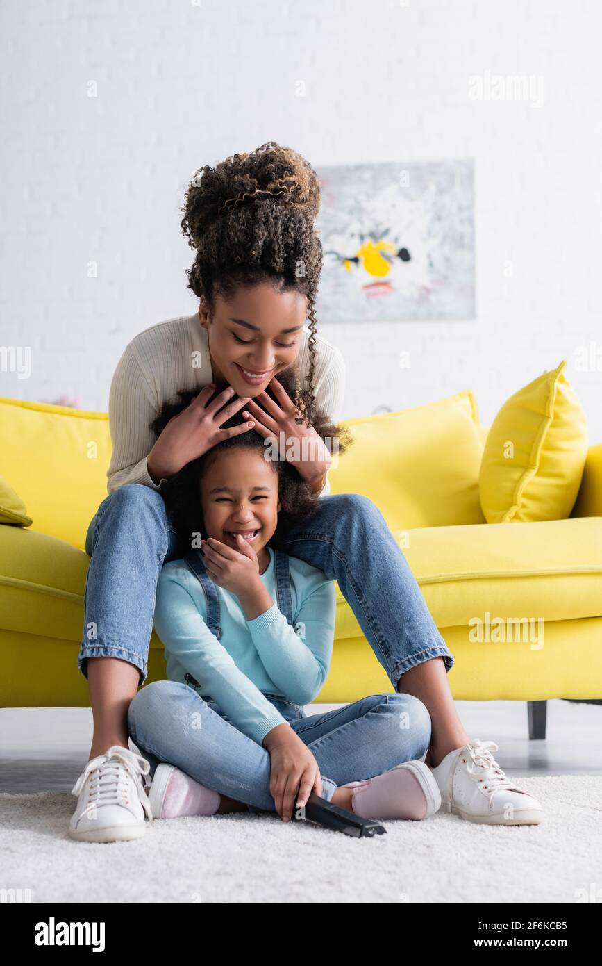 laughing african american child covering mouth with hand while watching ...