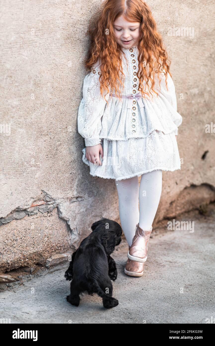 Little red hair girl playing with her new friend, cute black puppy ...