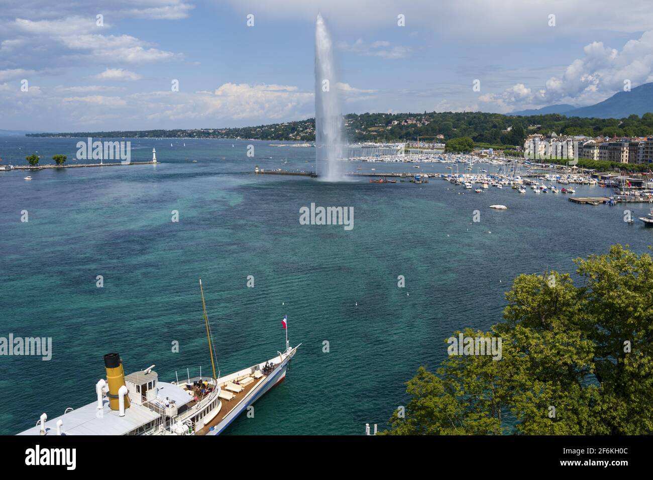 vintage steamboat arriving at a pier on Lake Geneva with the water jet ...