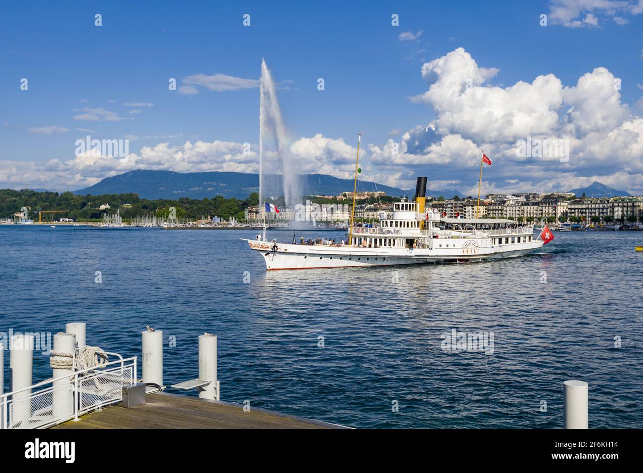 vintage steamboat arriving at a pier on Lake Geneva with the water jet ...
