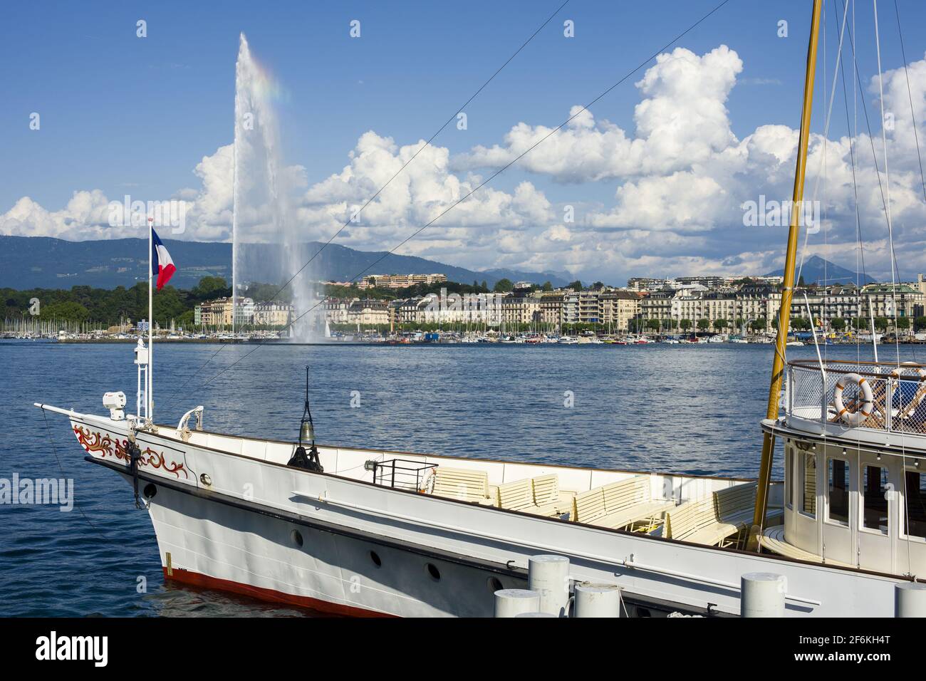 vintage steamboat arriving at a pier on Lake Geneva with the water jet ...