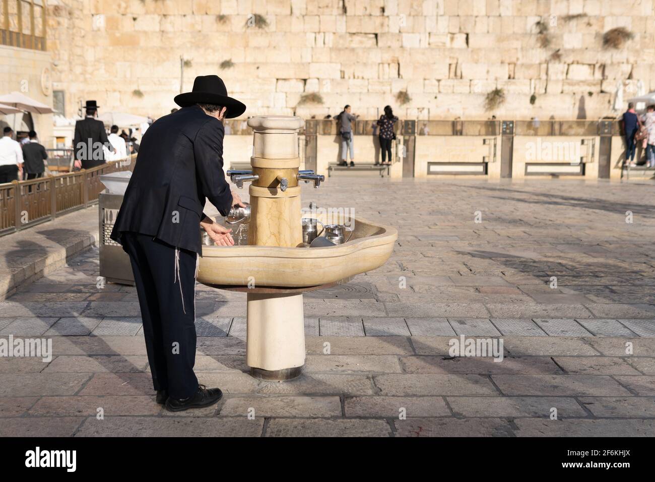 Jewish orthodox man wearing a black traditional suit and a hat washing ...