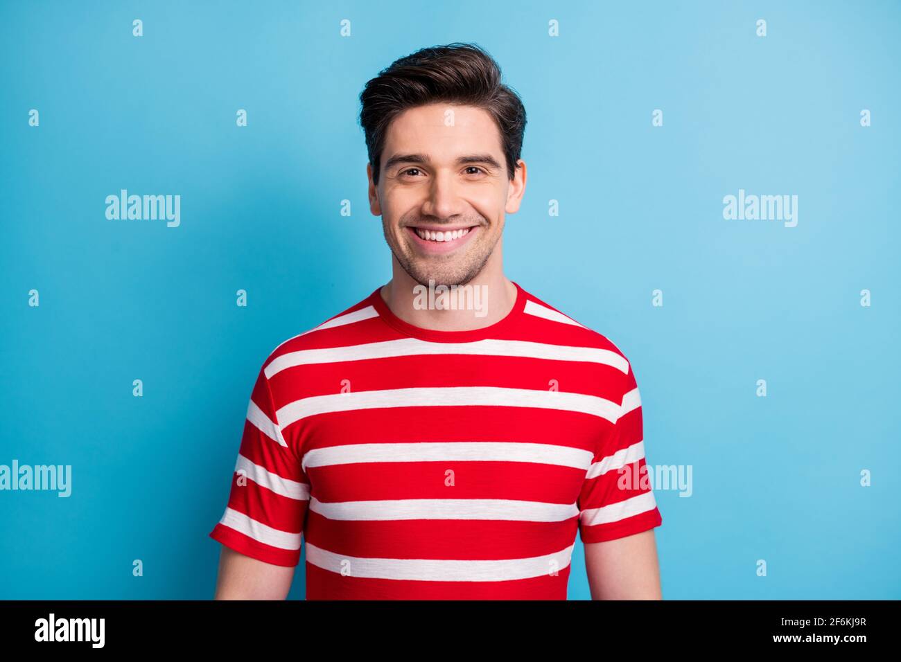 Photo of cute charming sweet man wear red outfit smiling isolated blue ...