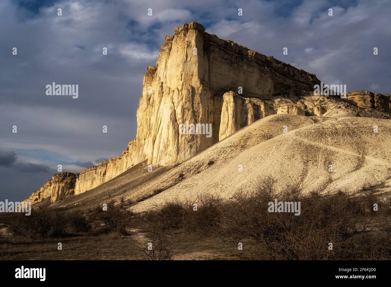 Beautiful white mountain peak lit by sun. White clouds and blue sky on ...
