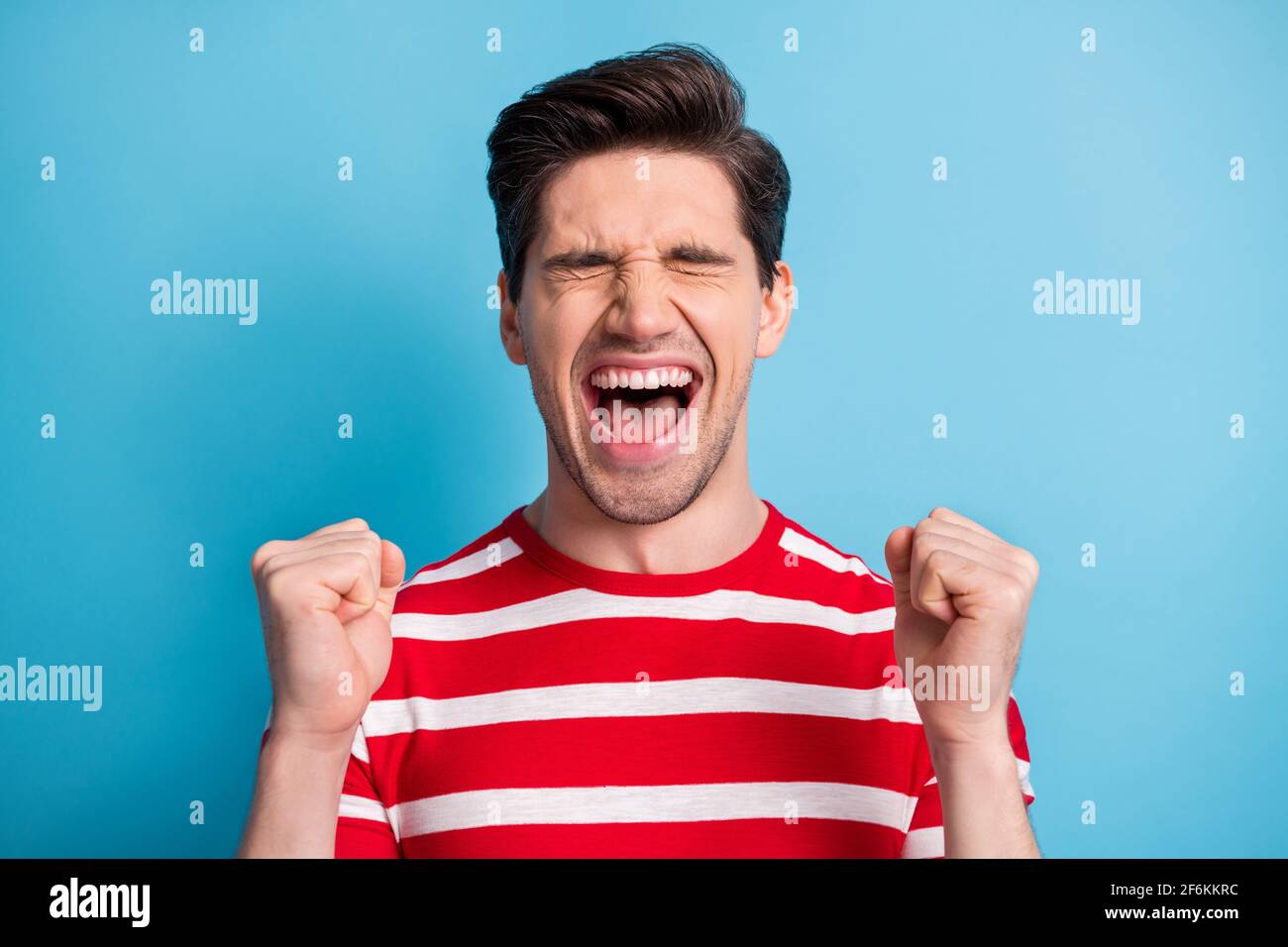 Photo of happy cheerful young man raise fists winner closed eyes scream ...