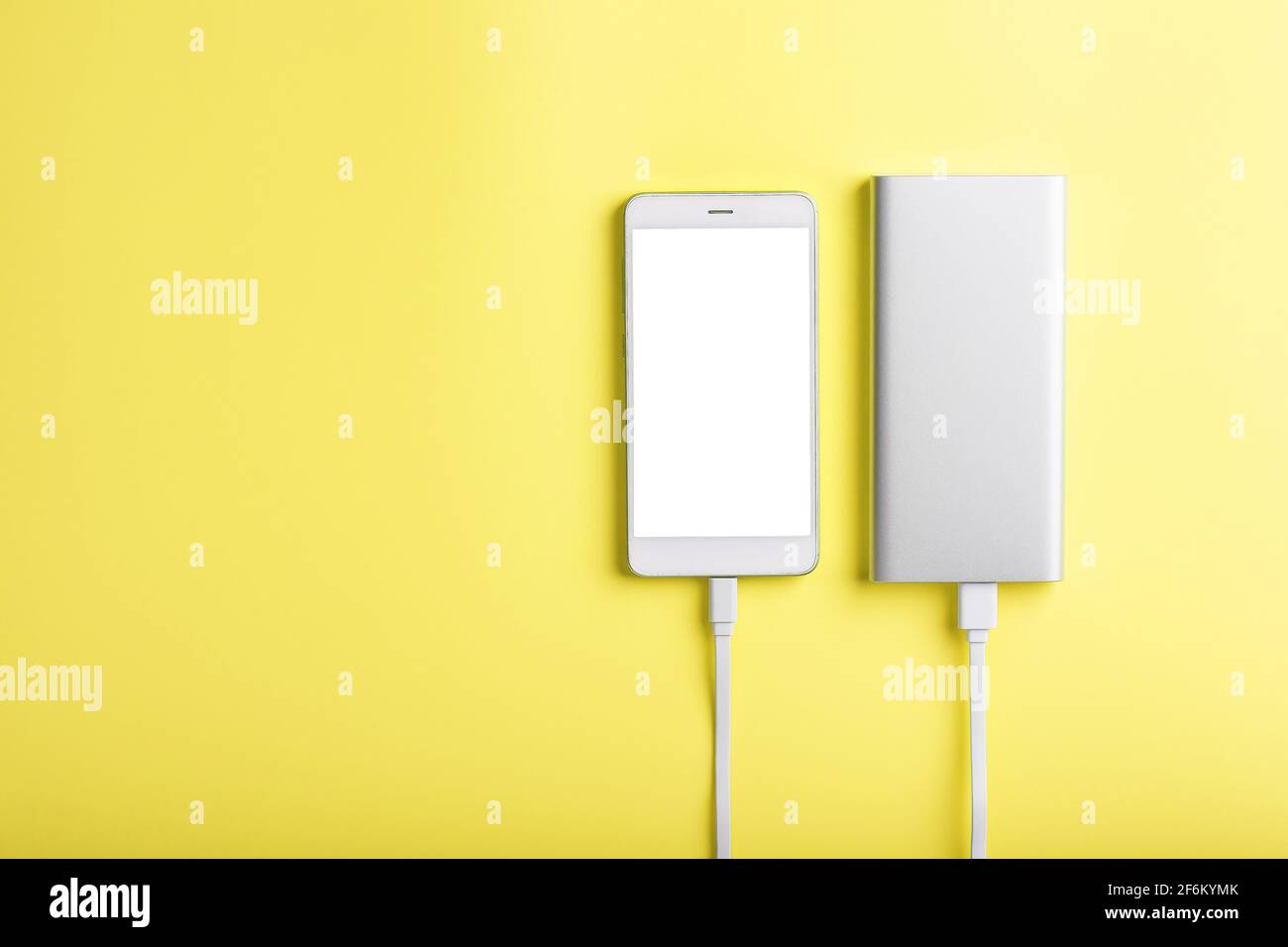Power Bank charges a smartphone on a yellow background. Universal ...