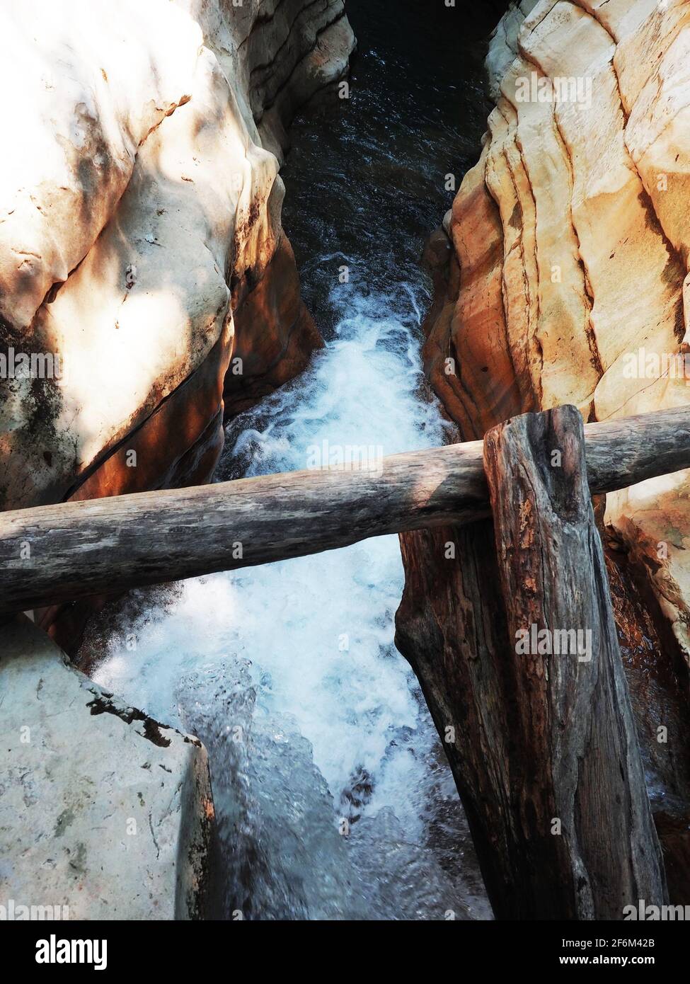 The log lies between the rocks above bubbling foamy narrow river Stock ...