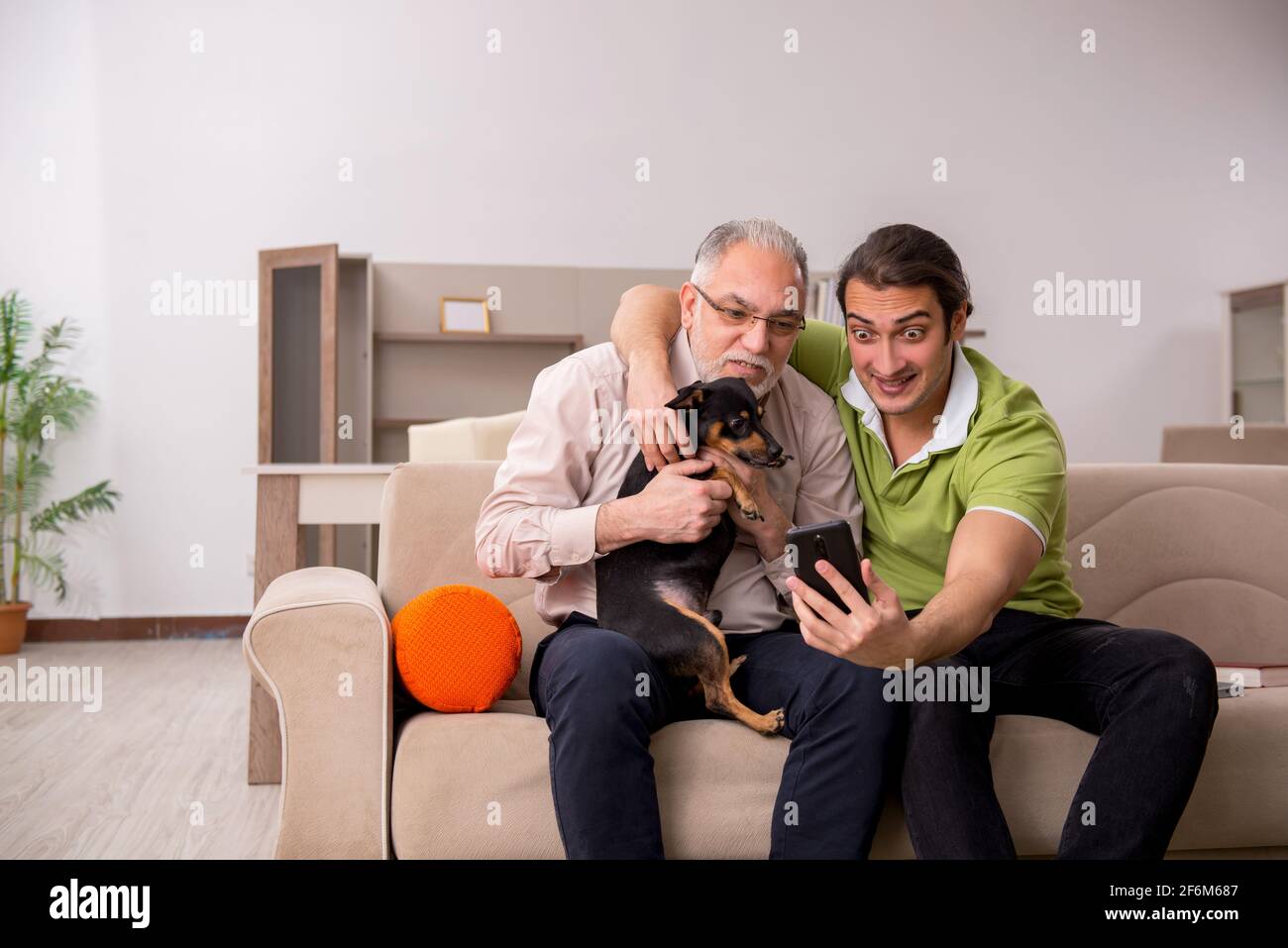 Two men with dog in the room Stock Photo - Alamy