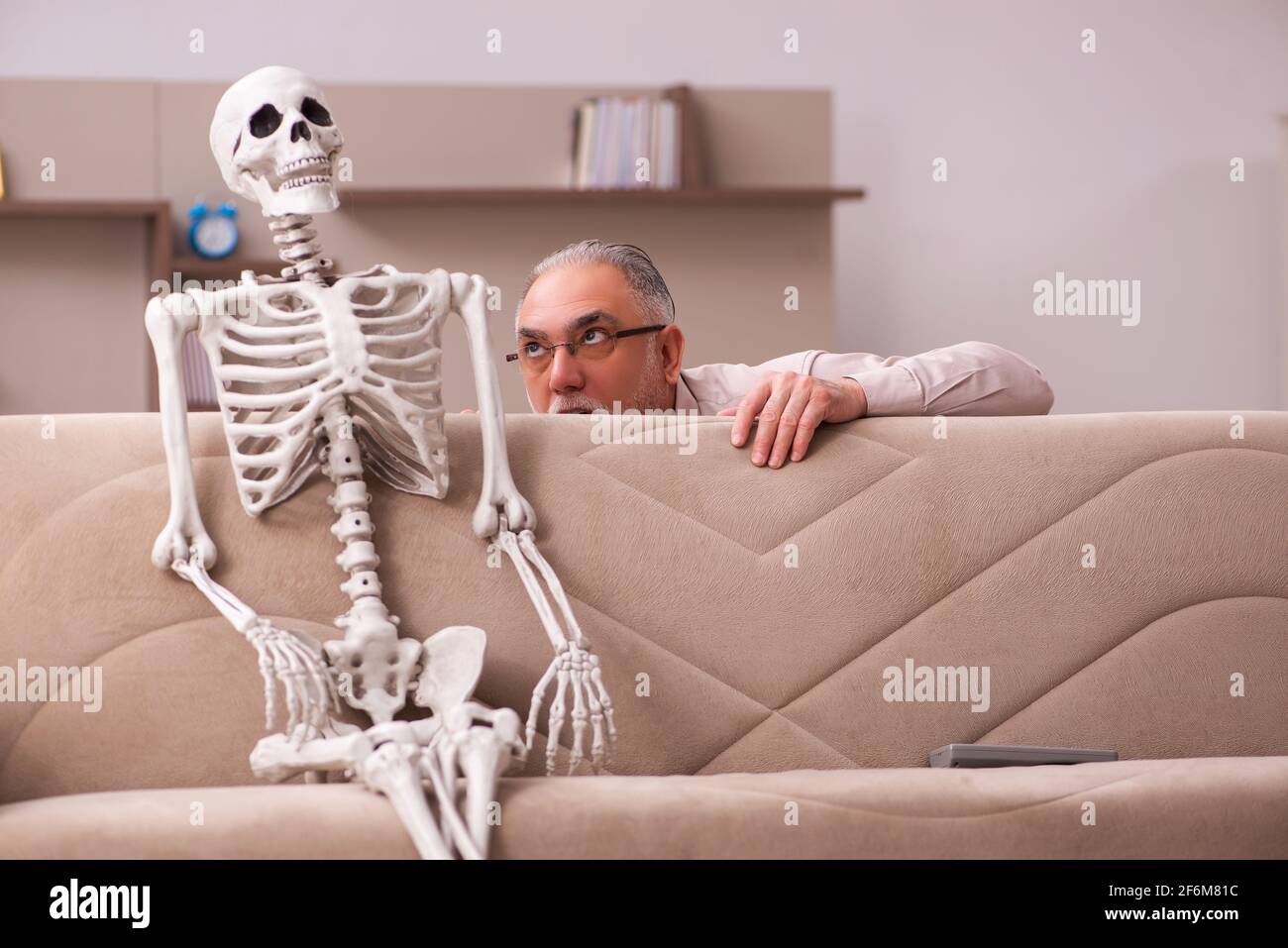 Old man sitting on the sofa with the female skeleton in undying love ...