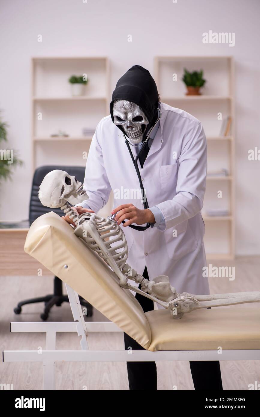 Devil doctor examining skeleton patient in the clinic Stock Photo - Alamy