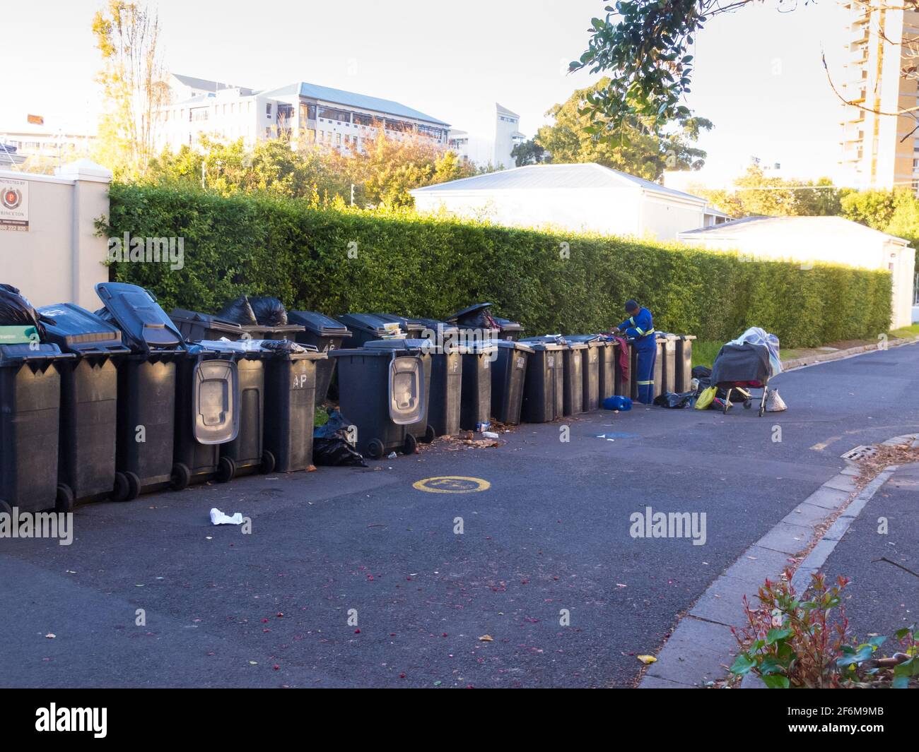 homeless man searches through garbage bins on the street during the ...