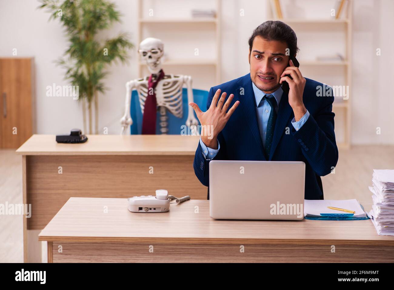 Dead employee working in the office in funny concept Stock Photo - Alamy