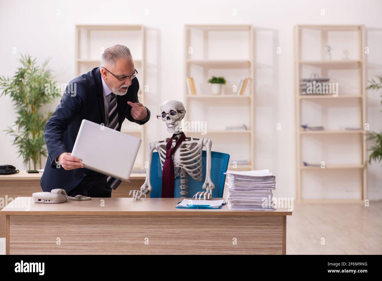 Dead employee working in the office in funny concept Stock Photo - Alamy