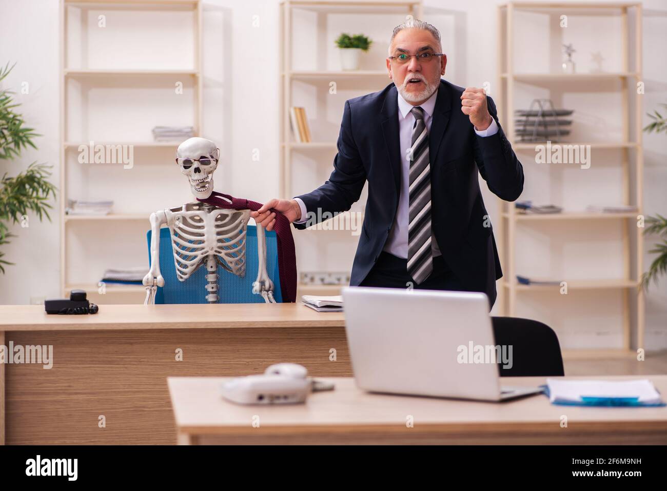 Dead employee working in the office in funny concept Stock Photo - Alamy