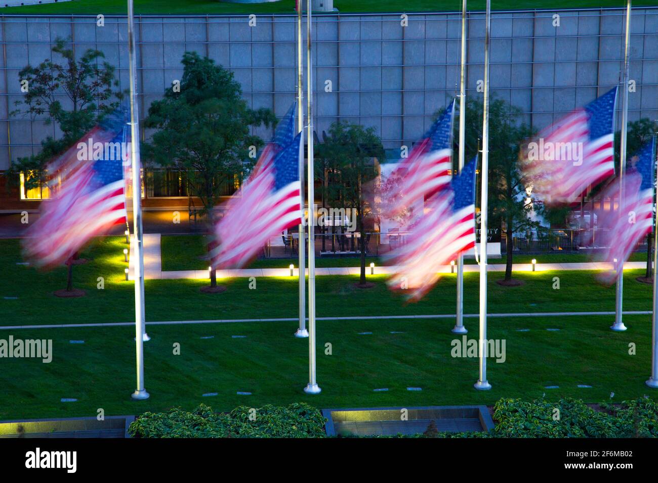 Motion blurred American flags at half mast blowing in the wind in front ...