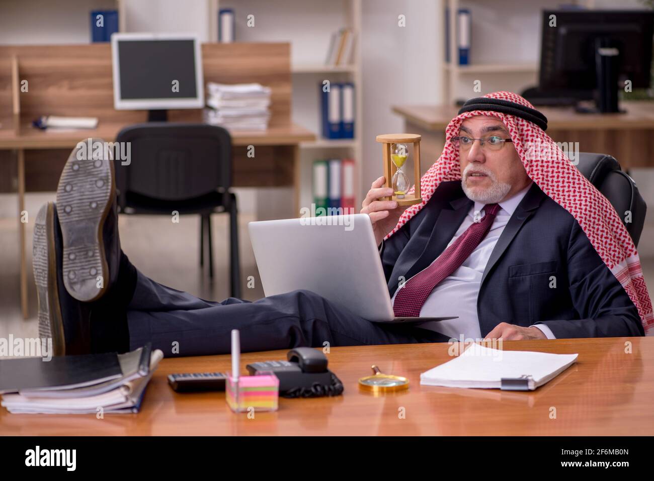 Aged male arab employee in time management concept Stock Photo - Alamy