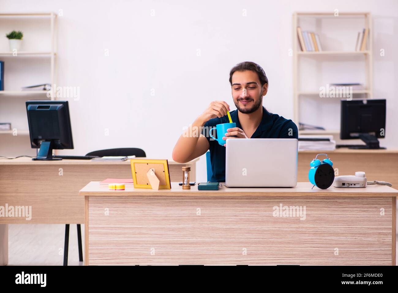 Young employee drinking coffee at workplace Stock Photo - Alamy