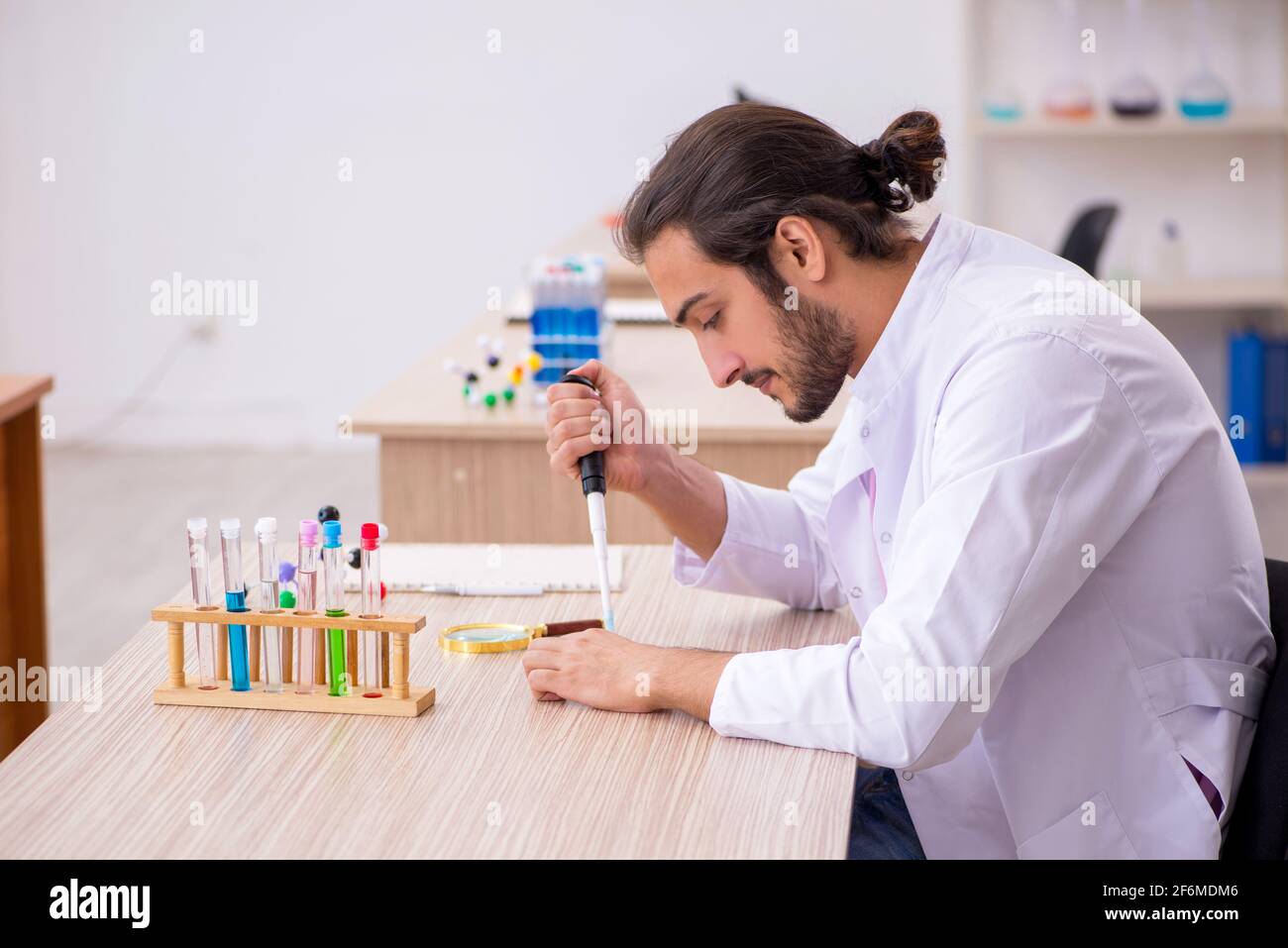 Young chemist sitting at the desk in the classroom Stock Photo - Alamy
