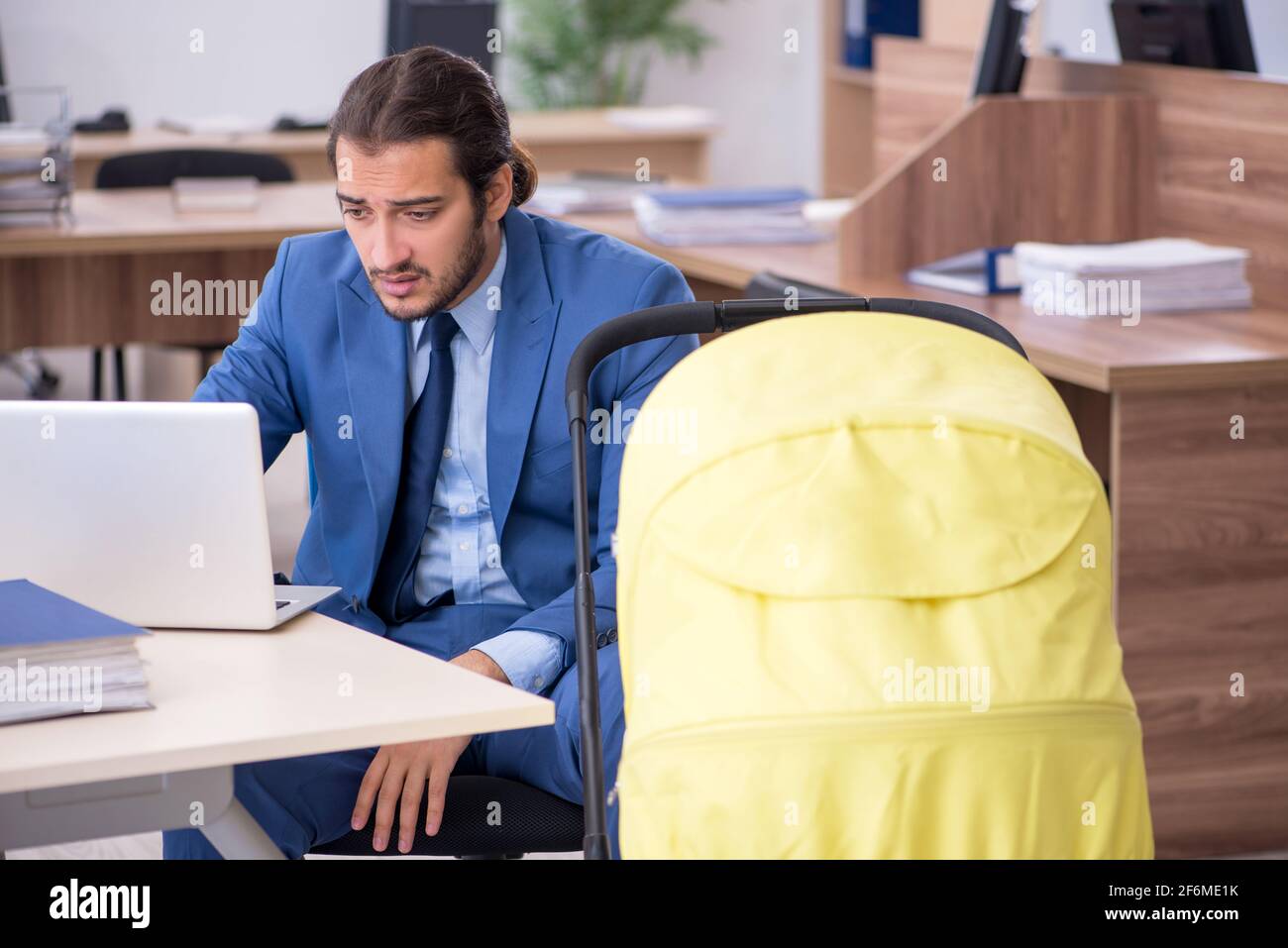 Young male employee looking after new born in the office Stock Photo ...