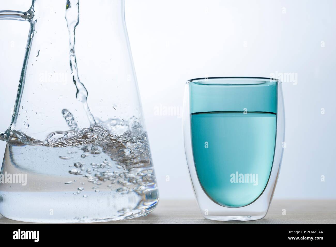 Flow of water is pouring into the green glass on white background Stock ...