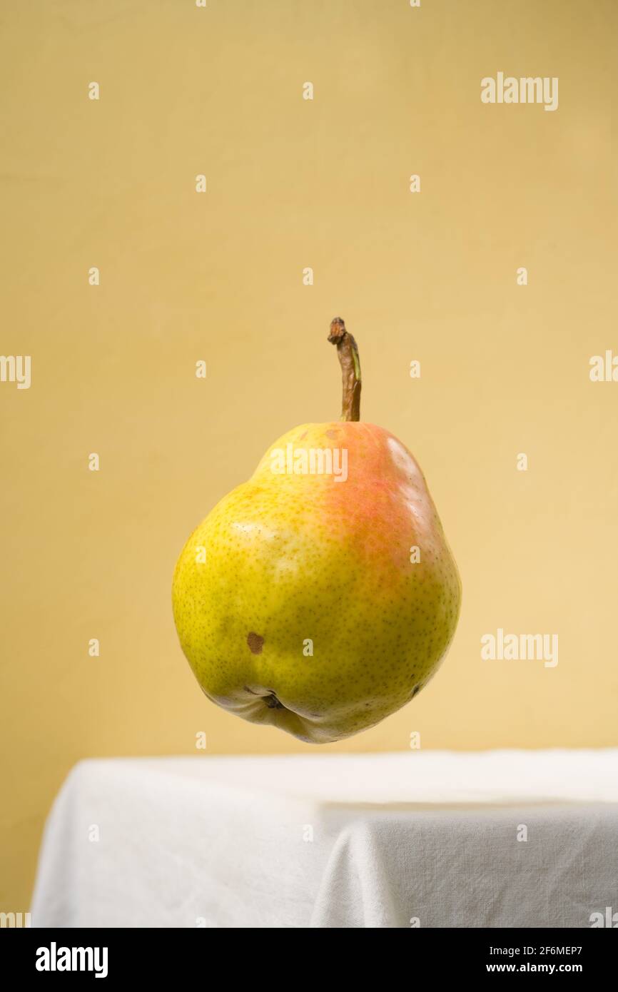 Pear floating in the air on a white table and yellow background Stock ...