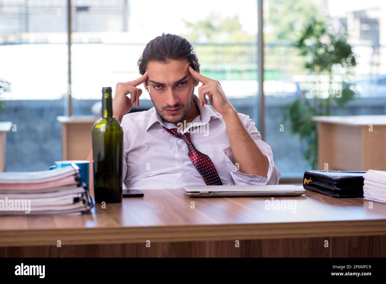 Young alcohol addicted employee working in the office Stock Photo - Alamy