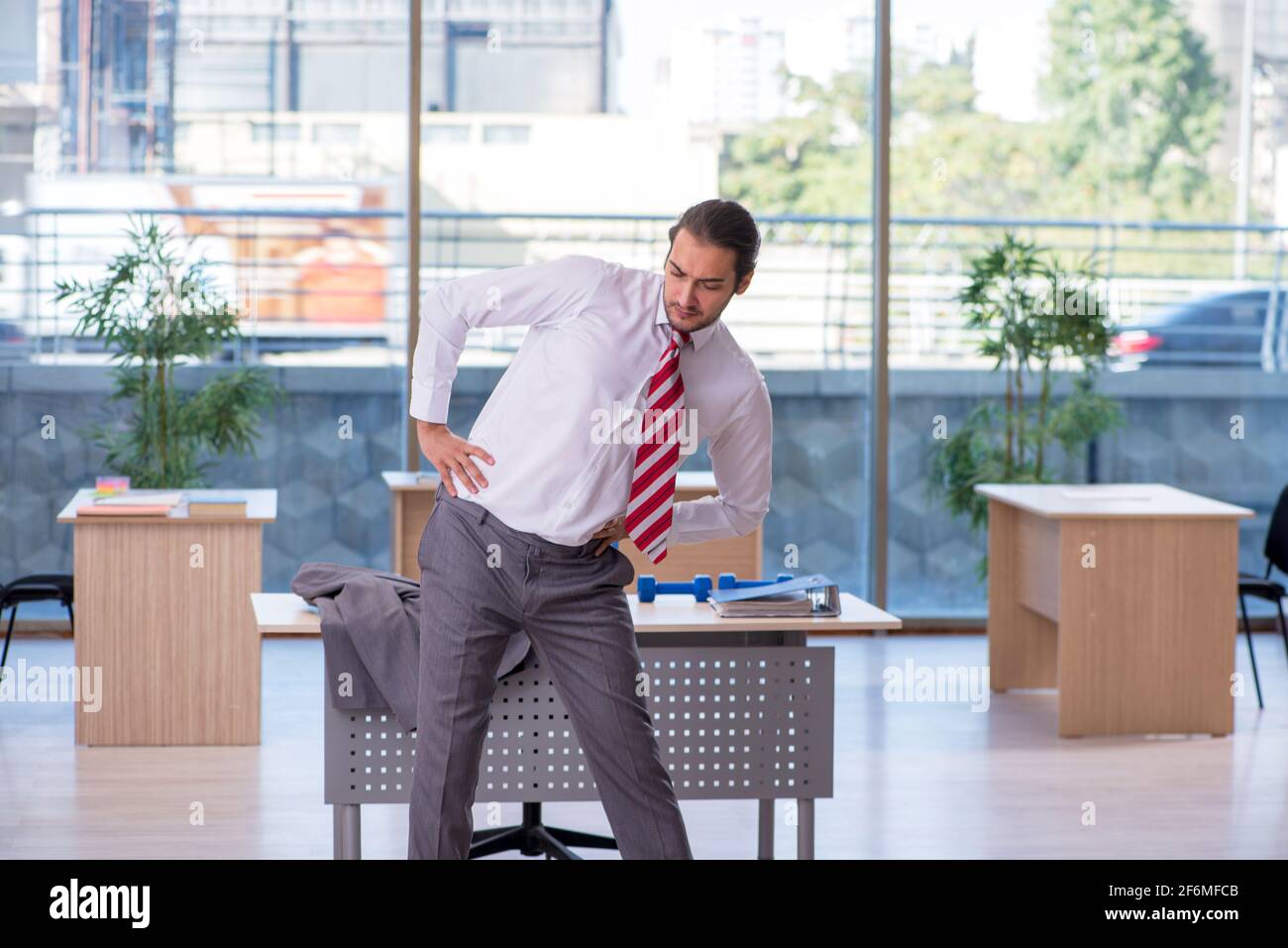 Young employee doing sport exercises at workplace Stock Photo - Alamy
