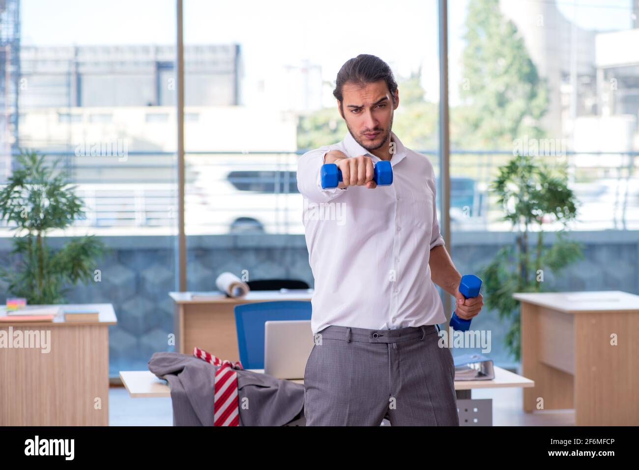 Young employee doing sport exercises at workplace Stock Photo - Alamy