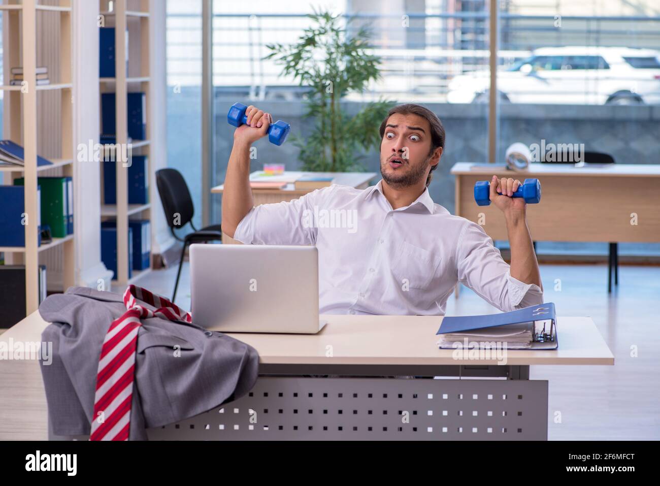 Young employee doing sport exercises at workplace Stock Photo - Alamy