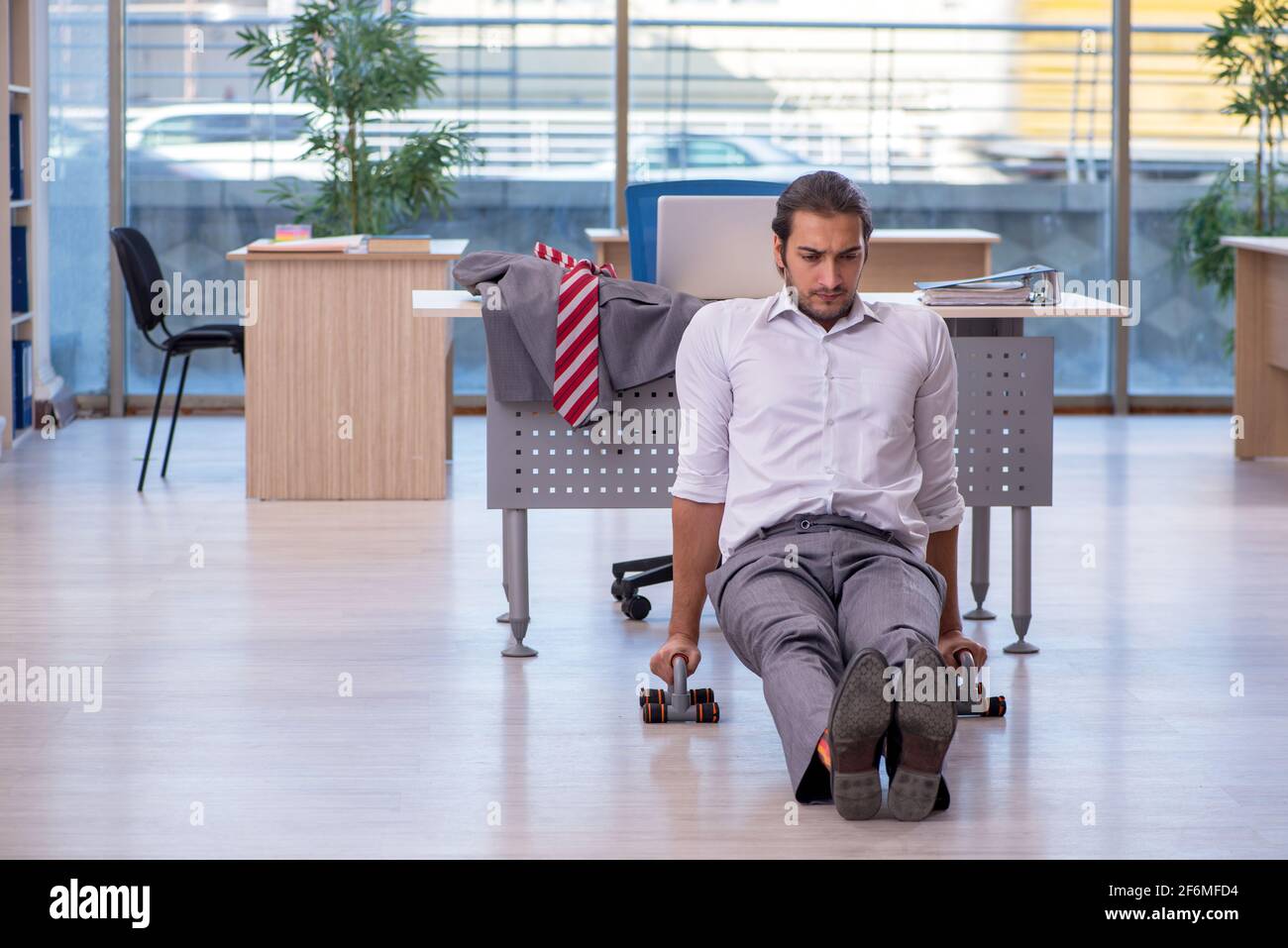 Young employee doing sport exercises at workplace Stock Photo - Alamy
