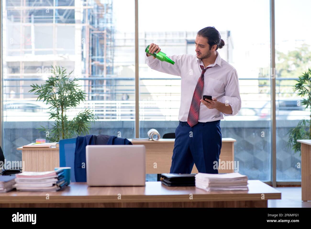 Young alcohol addicted employee working in the office Stock Photo - Alamy